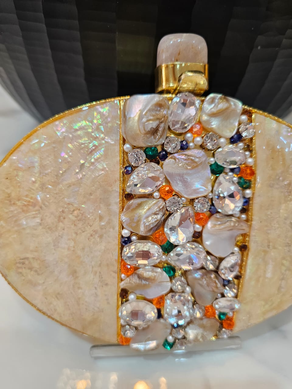 Oval metallic clutch with shell crystal colouring moti in middle and ...